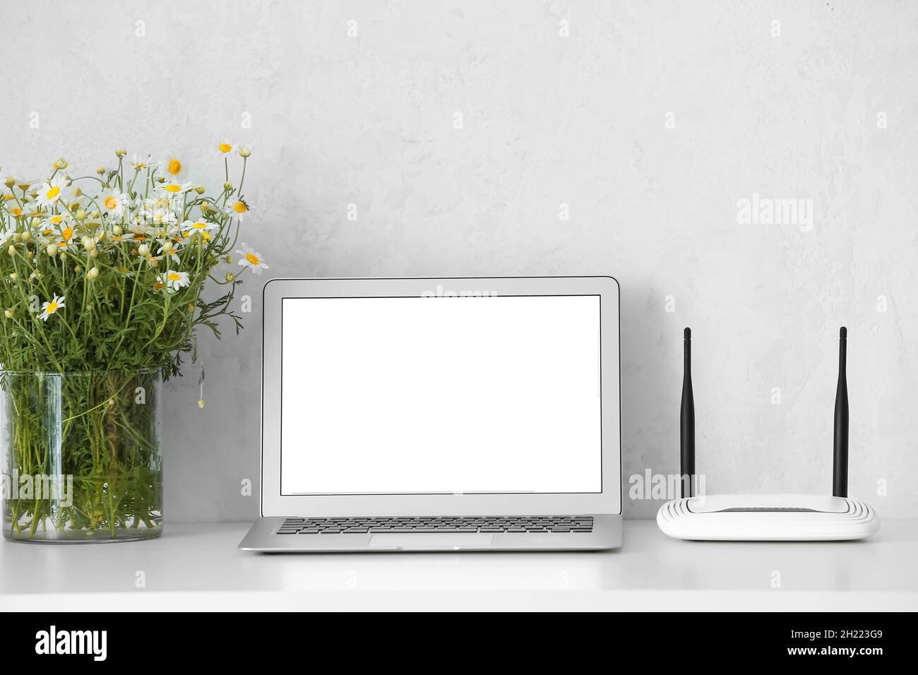 Modern wi-fi router and laptop on table near white wall Stock Photo - Alamy