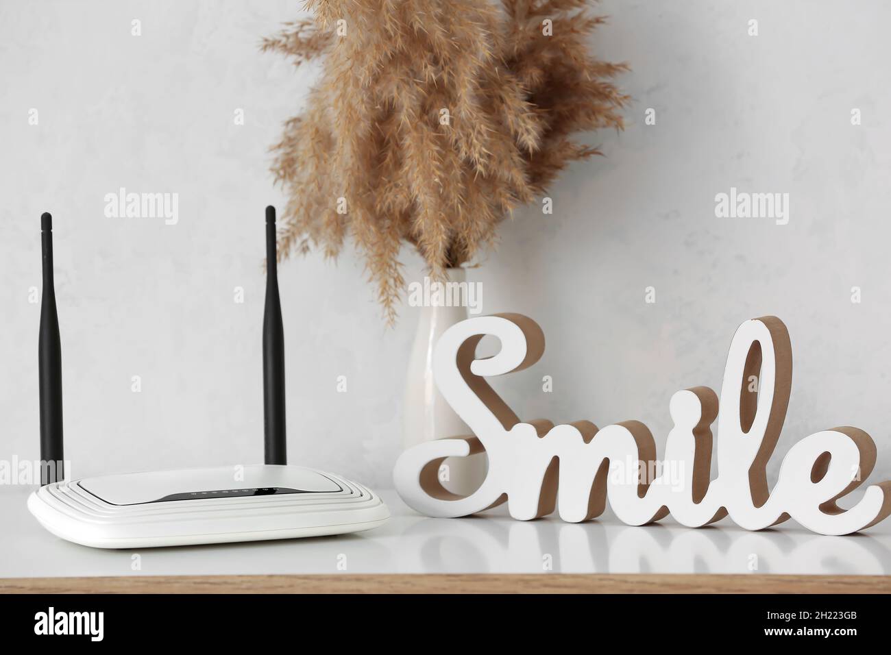 Modern wi-fi router and decor element on table near white wall Stock ...