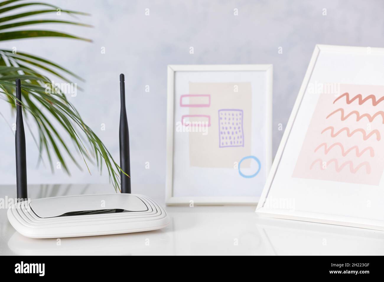 Modern wi-fi router and pictures on table near white wall Stock Photo ...