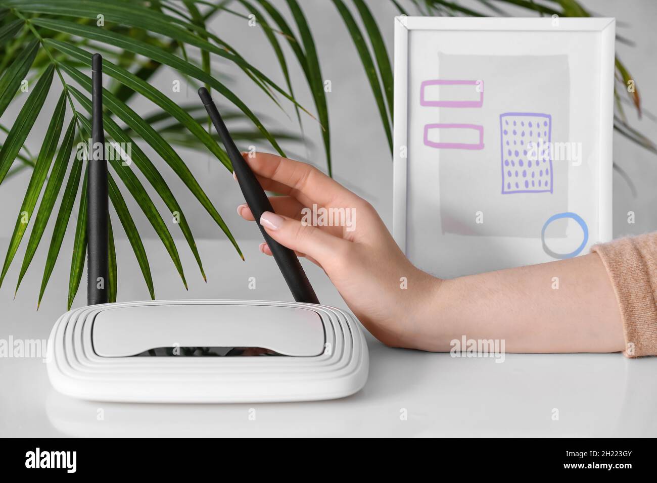 Female hand with wi-fi router on table in room Stock Photo - Alamy