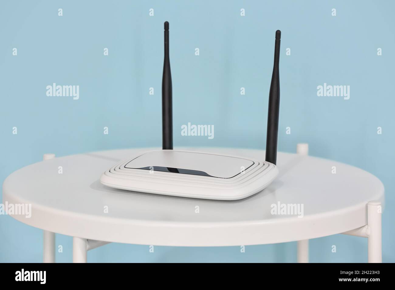 Modern wi-fi router on table near blue wall Stock Photo - Alamy