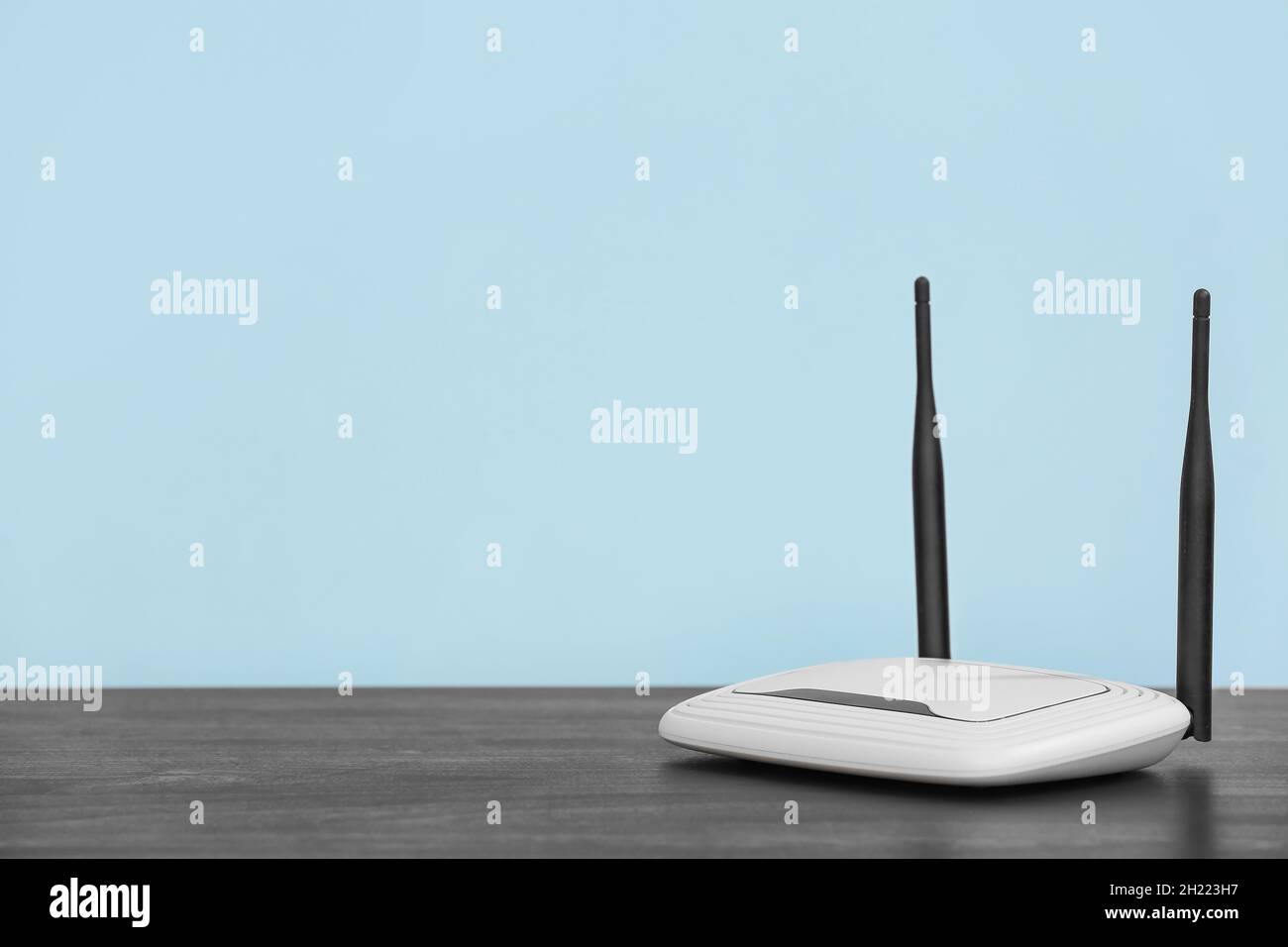 Modern wi-fi router on table near blue wall Stock Photo - Alamy