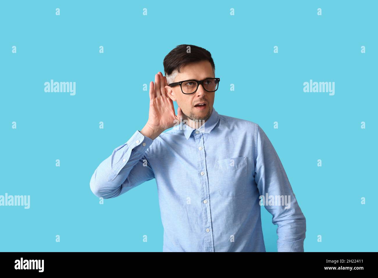 Man trying to hear something on color background Stock Photo - Alamy
