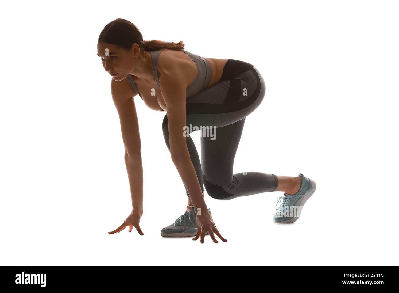 Silhouette of sporty young woman in crouch start position on white ...