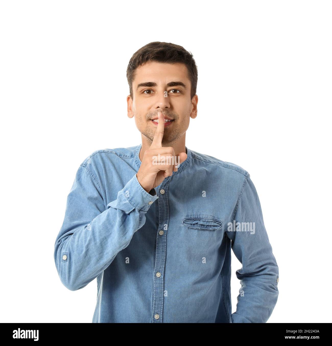Young gossip man showing silence gesture on white background Stock ...