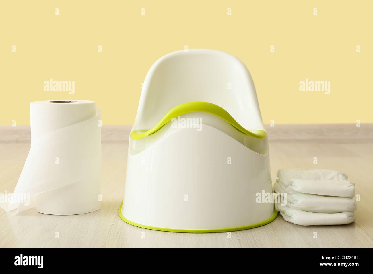 Potty, diapers and toilet paper rolls on floor near color wall Stock ...