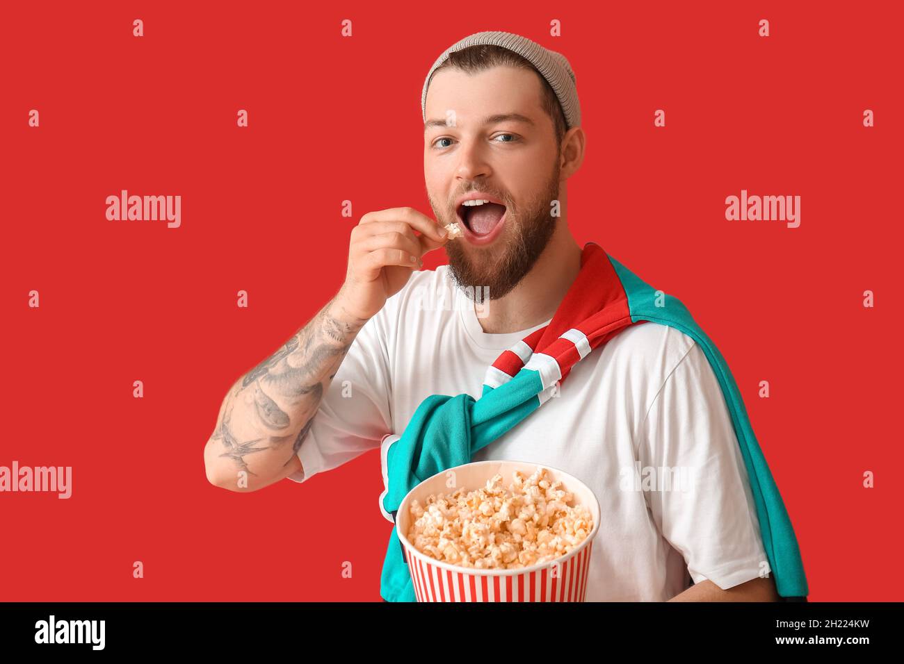 Young guy eating popcorn on color background Stock Photo - Alamy