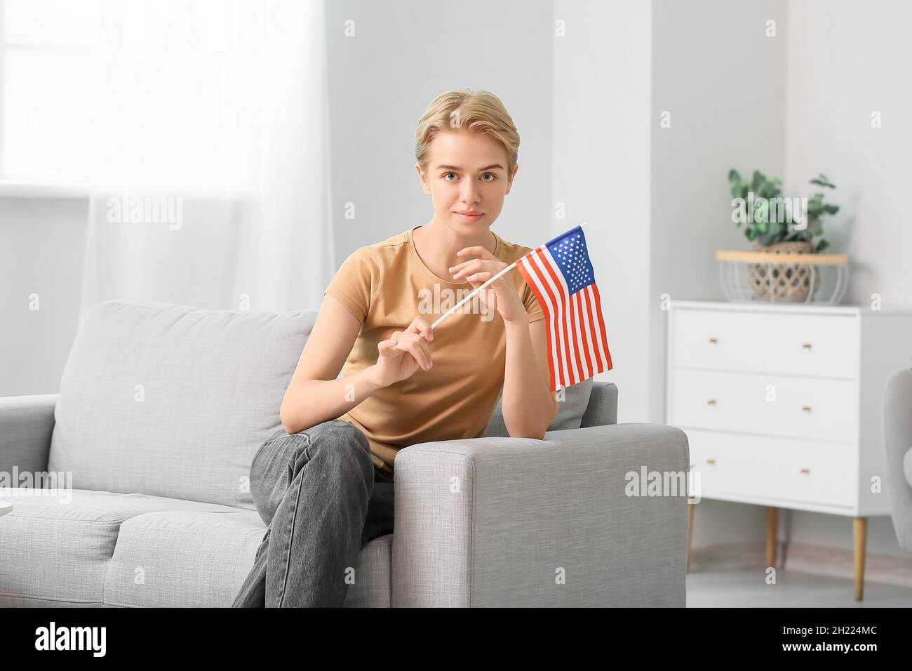 Young woman with USA flag sitting on sofa at home Stock Photo - Alamy
