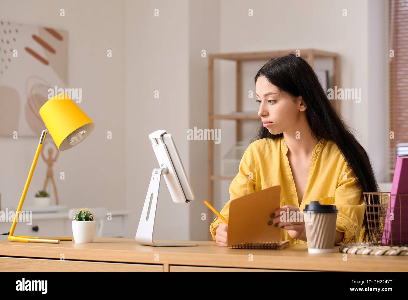 Beautiful teenage girl writing in notebook at table Stock Photo - Alamy