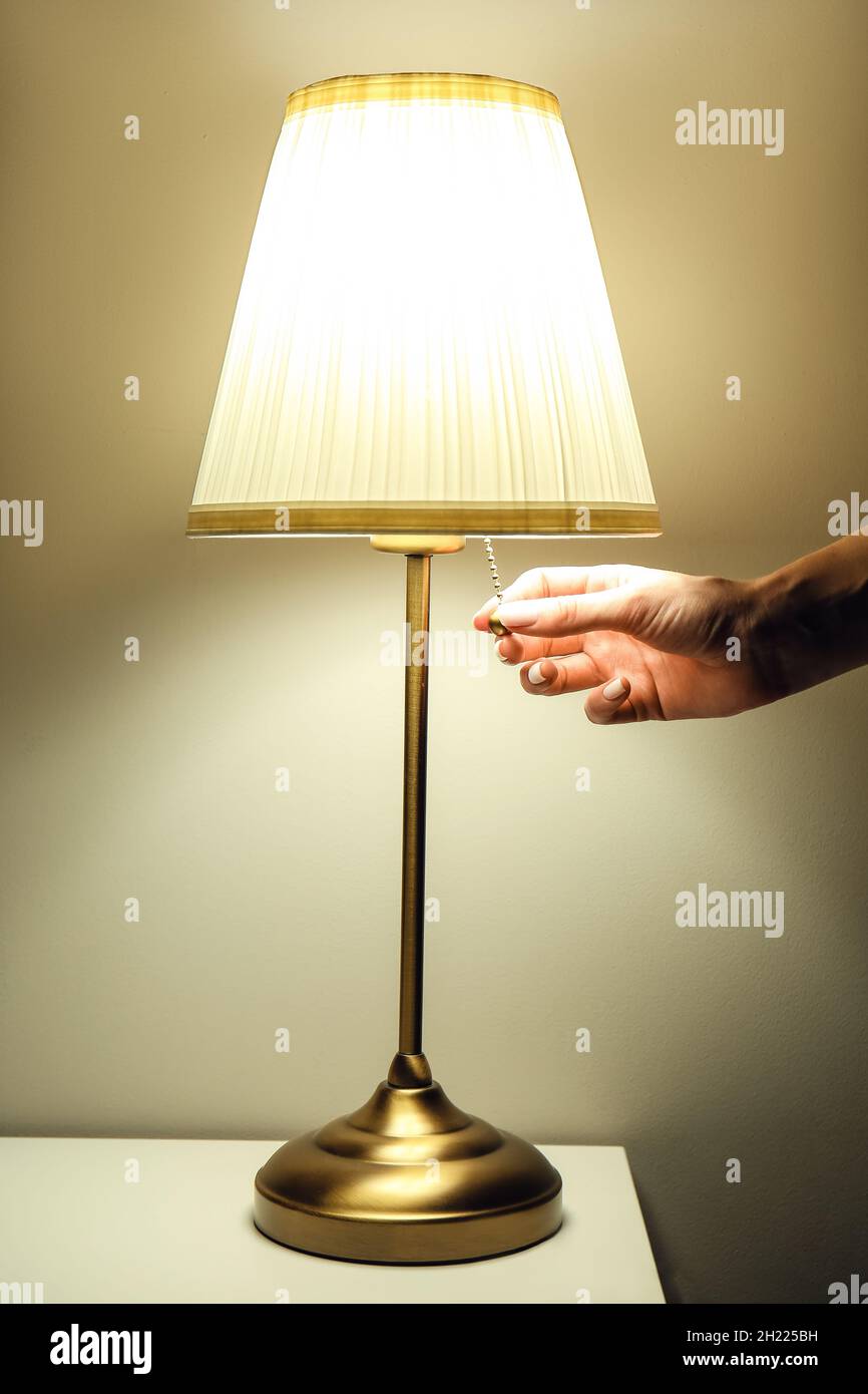 Woman turning off lamp in dark room Stock Photo - Alamy