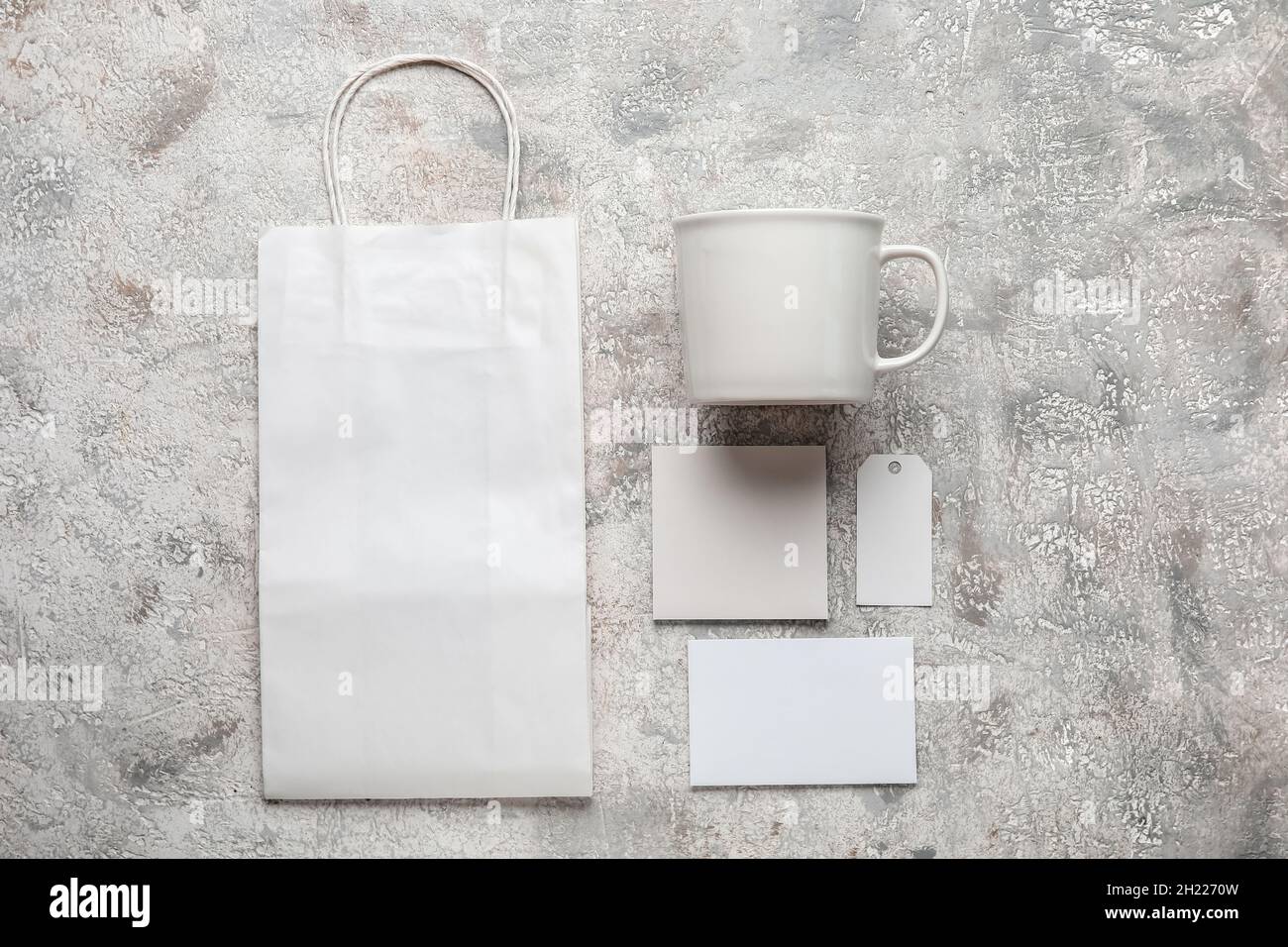 Composition with cup, blank paper bag and cards on light background ...