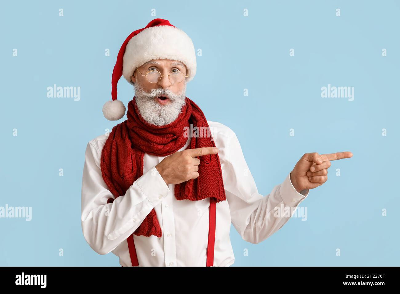 Portrait of surprised Santa Claus pointing at something on color ...