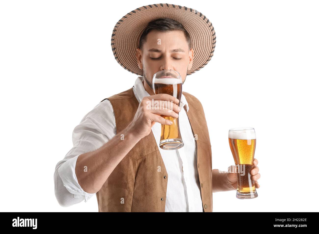 Young man in traditional German clothes drinking beer on white ...