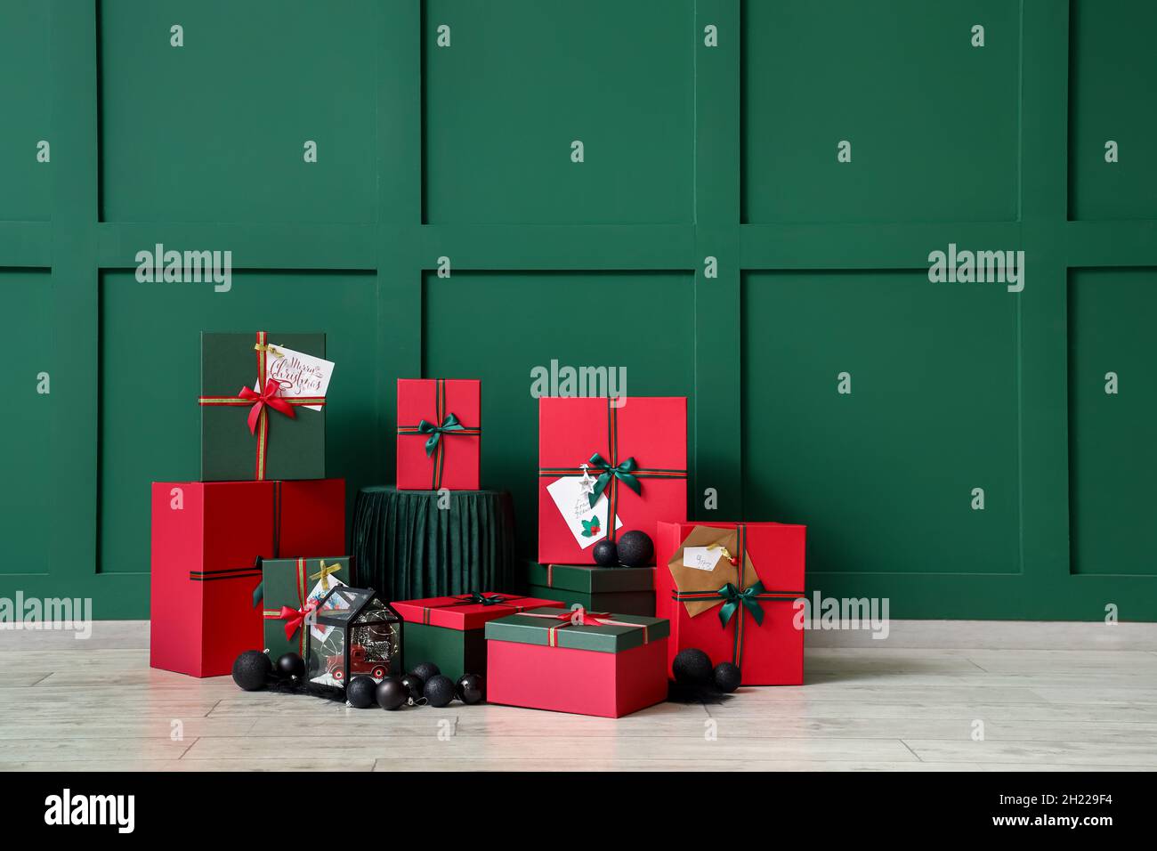 Christmas gift boxes and balls near green wall Stock Photo - Alamy