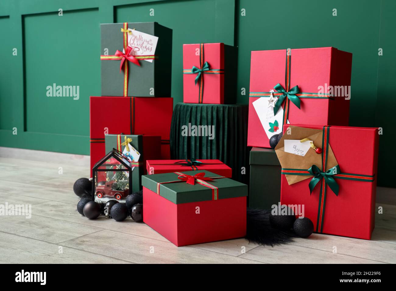 Christmas gift boxes and balls near green wall Stock Photo - Alamy