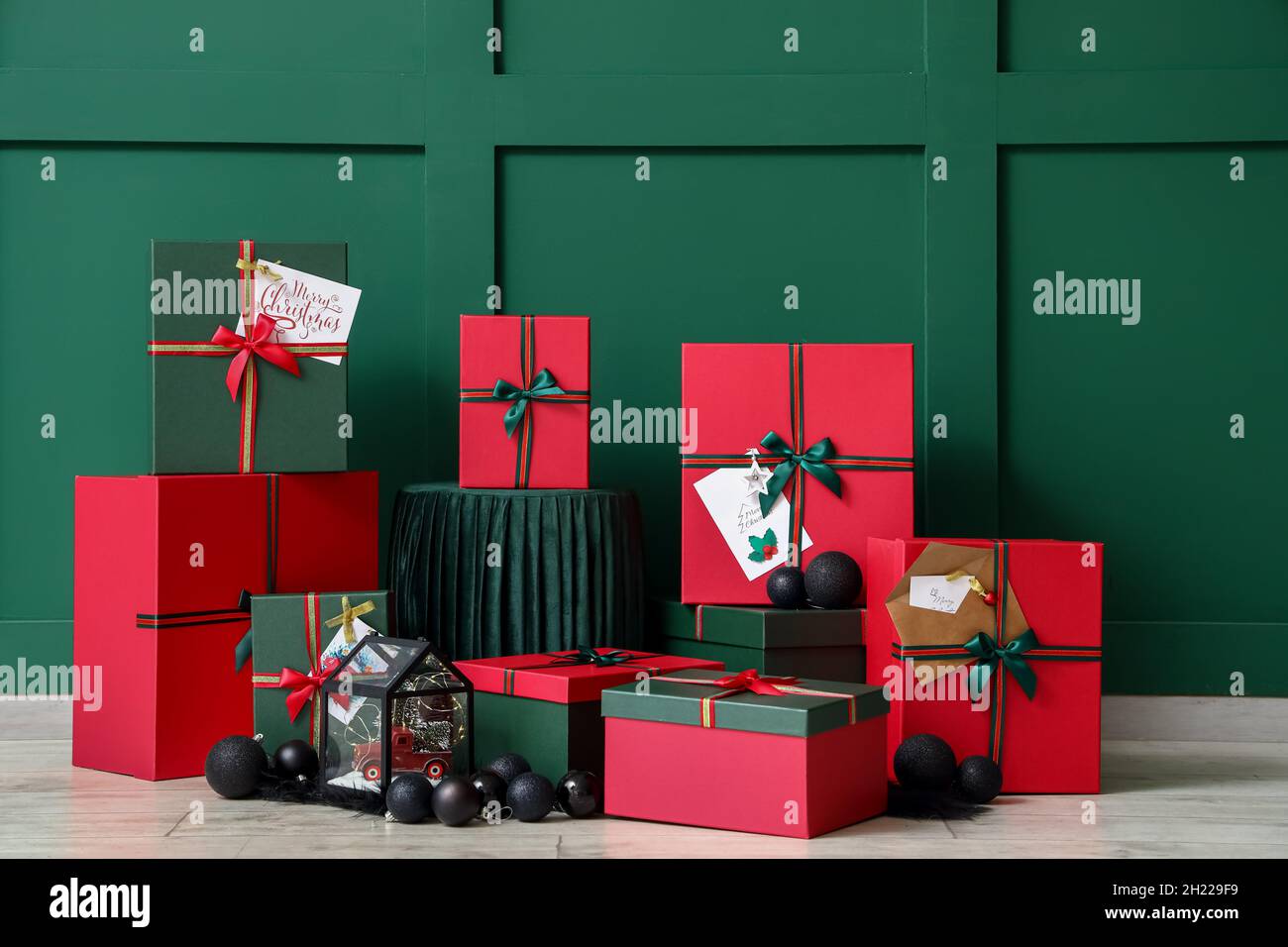 Christmas gift boxes and balls near green wall Stock Photo - Alamy