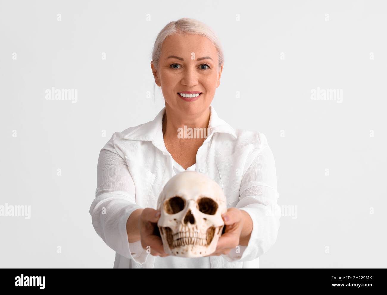 Woman holding human skull on white background Stock Photo - Alamy