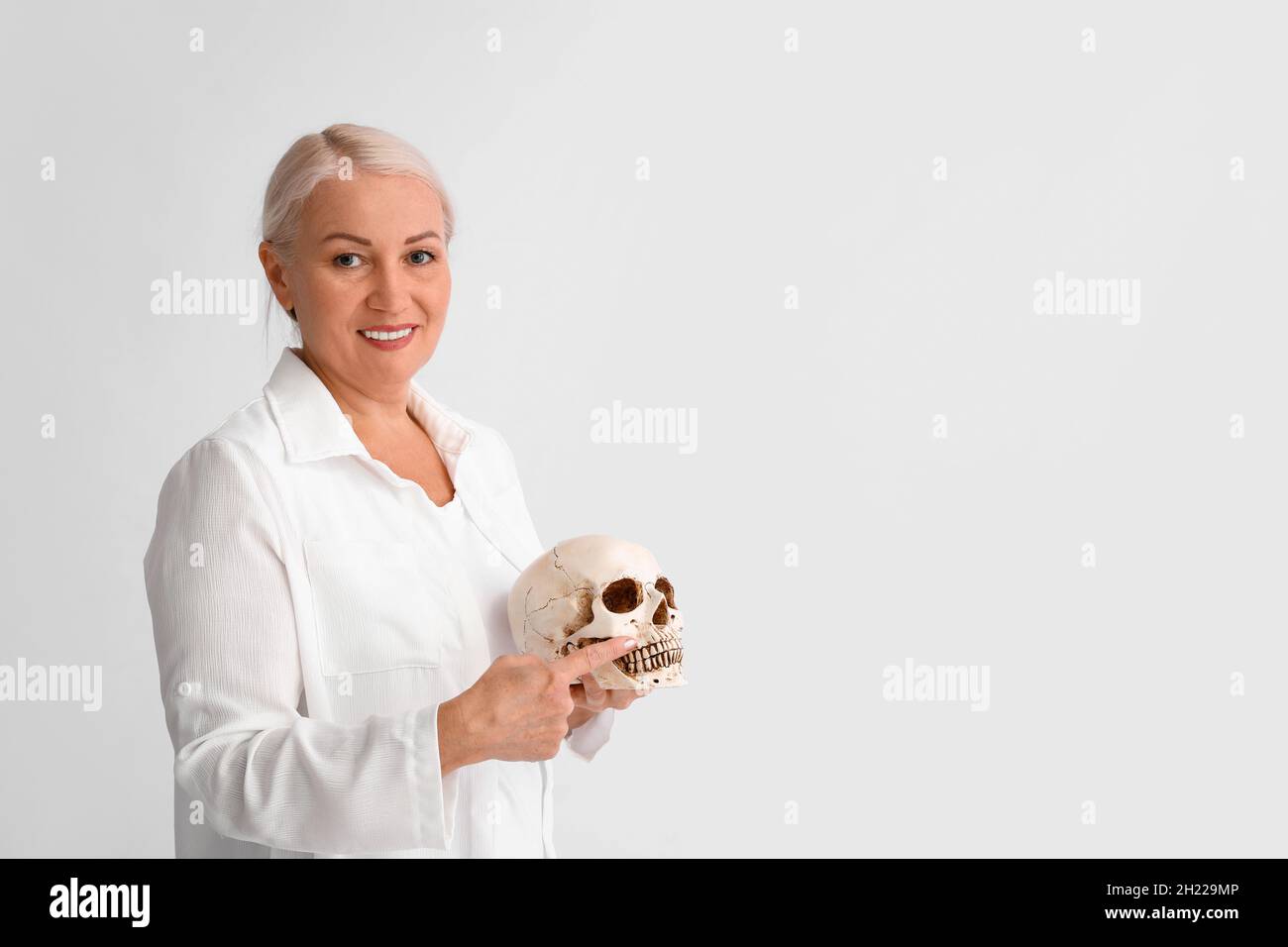 Woman holding human skull on white background Stock Photo - Alamy