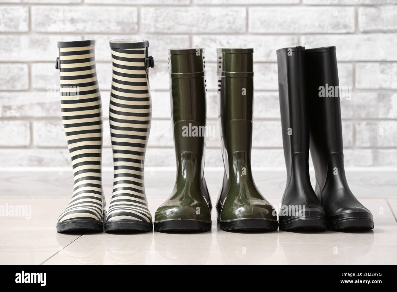 Different rubber boots on floor near brick wall Stock Photo - Alamy