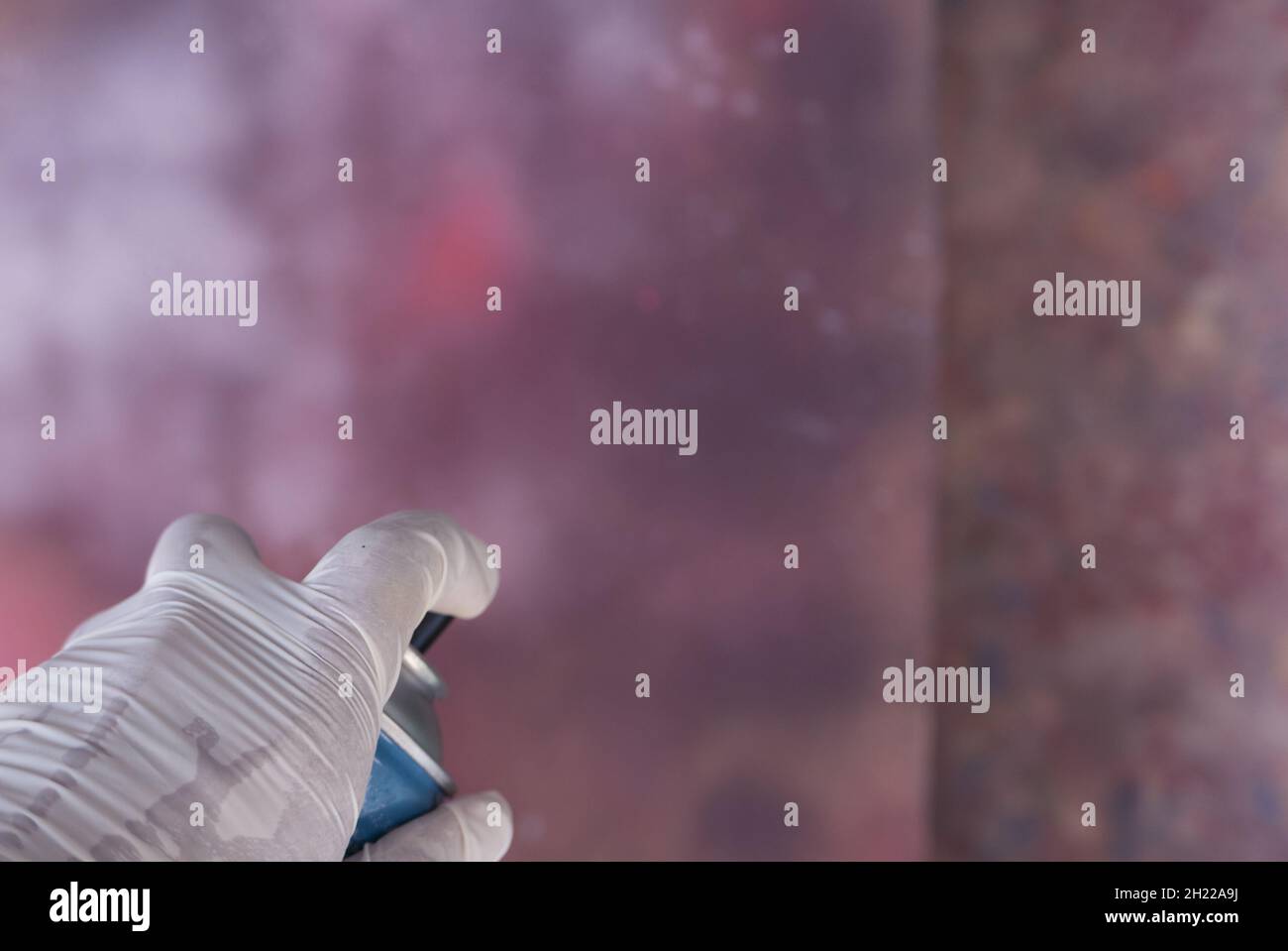 Hand wearing a latex glove and spraying blue paint from a graffiti can ...