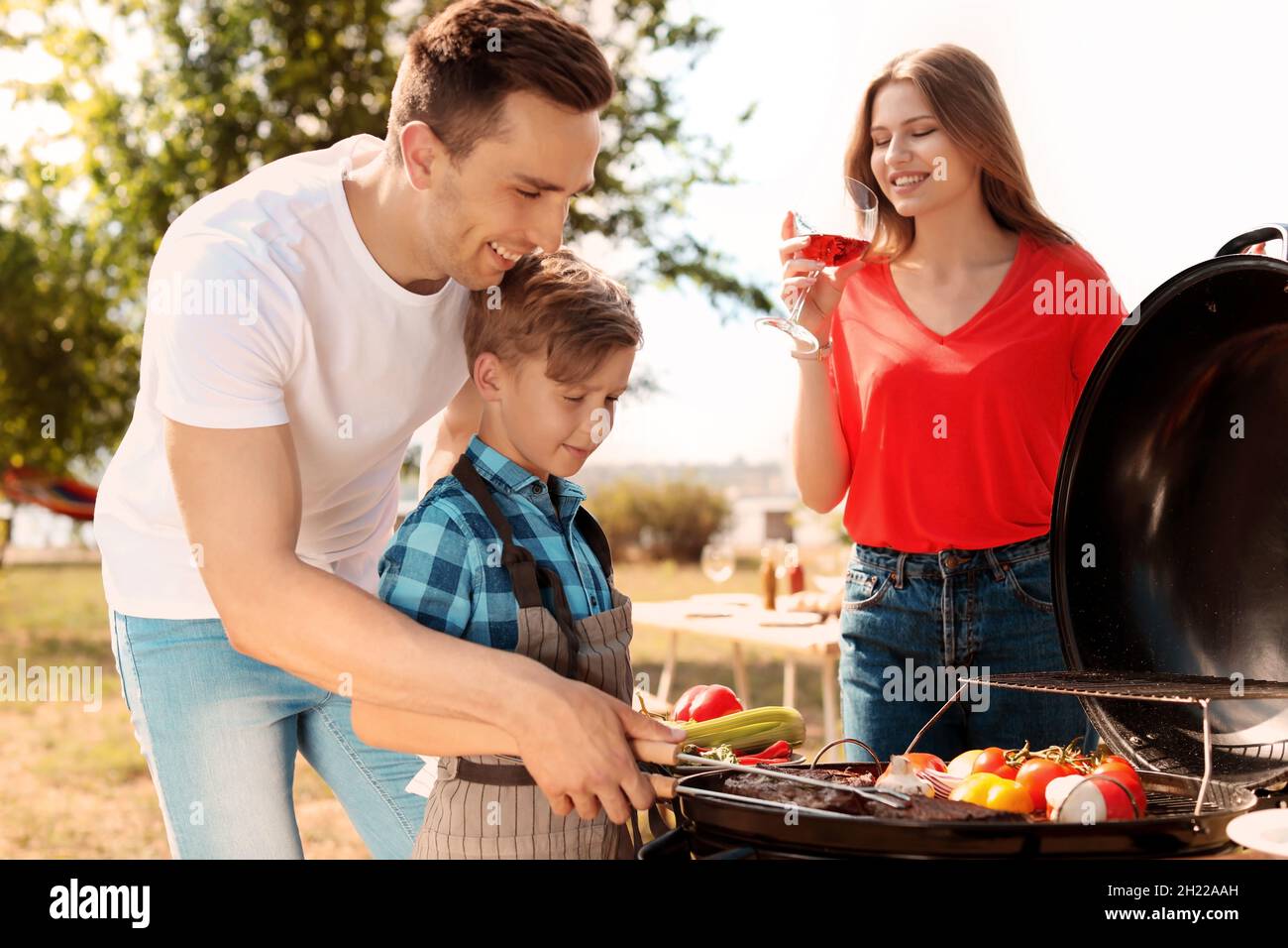 Happy family having barbecue with modern grill outdoors Stock Photo - Alamy