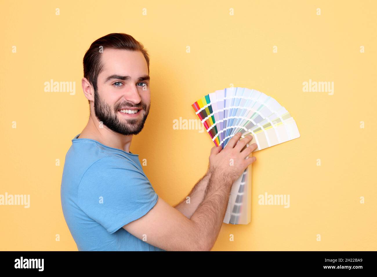 Young man with color palette on yellow background Stock Photo - Alamy