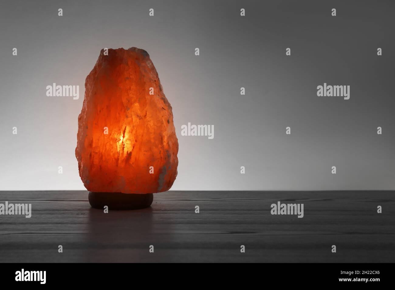 Himalayan salt lamp on table against dark background Stock Photo - Alamy