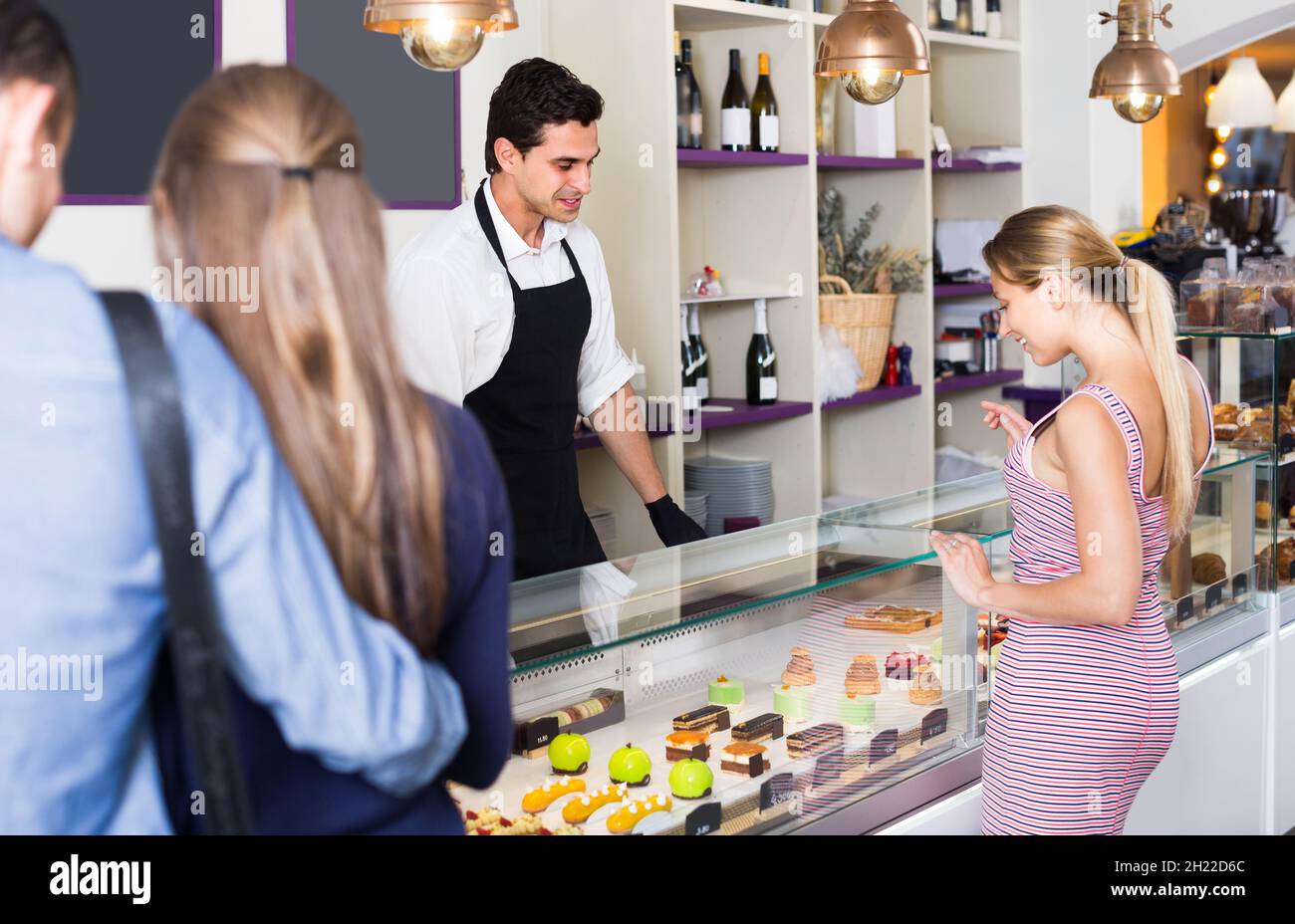 Visitors are choosing delicious cakes from showcase Stock Photo - Alamy