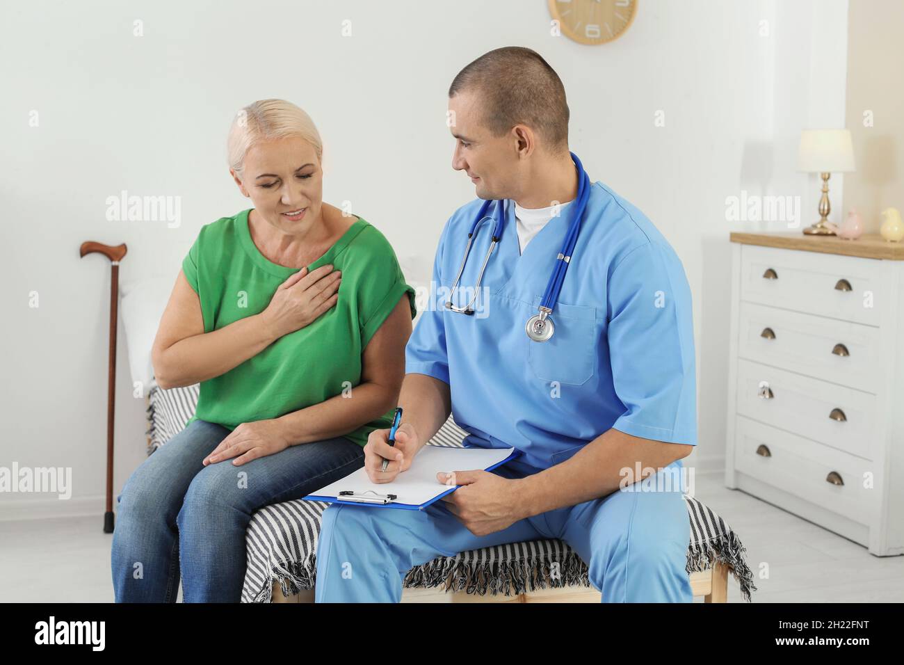 Male medical assistant consulting female patient during home visit ...