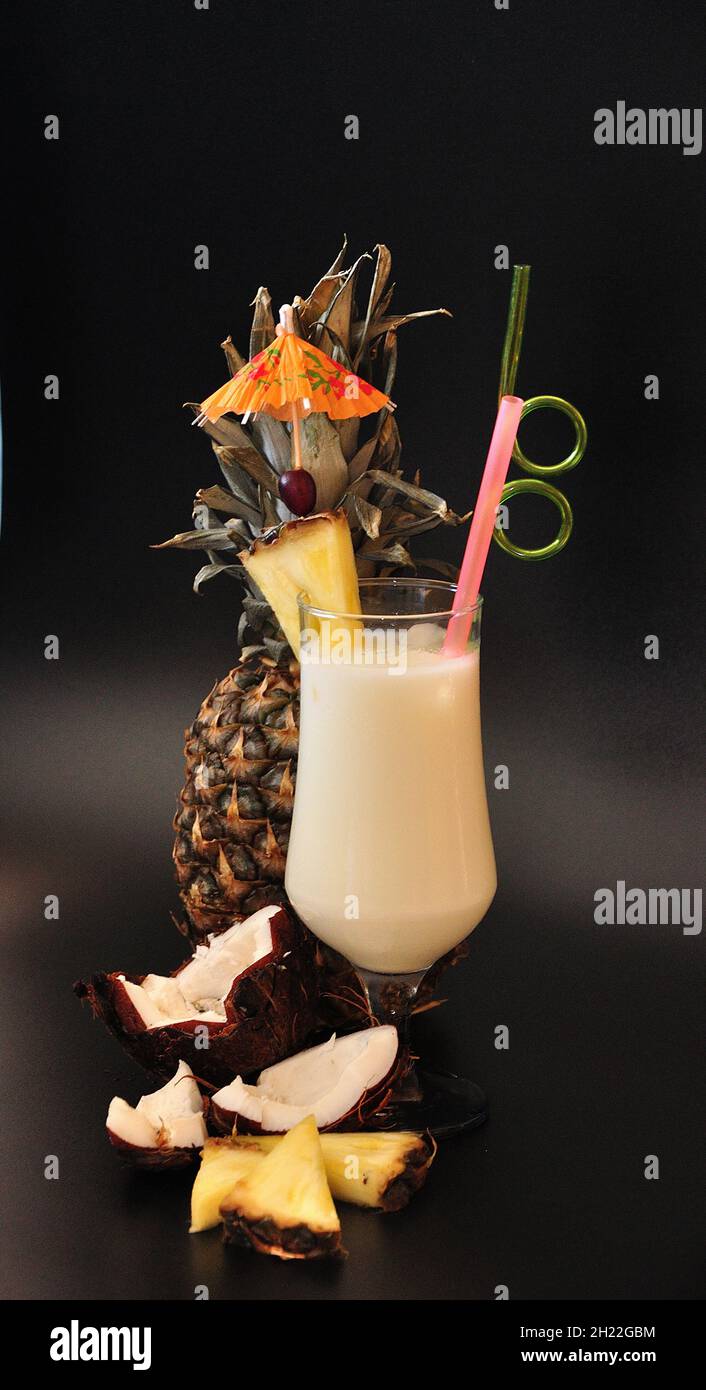 A tall glass of Pina Colada cocktail on a black background, next to a ...