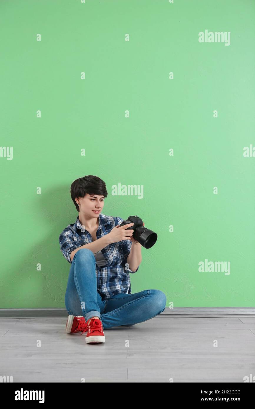 Young female photographer with camera near color wall Stock Photo - Alamy