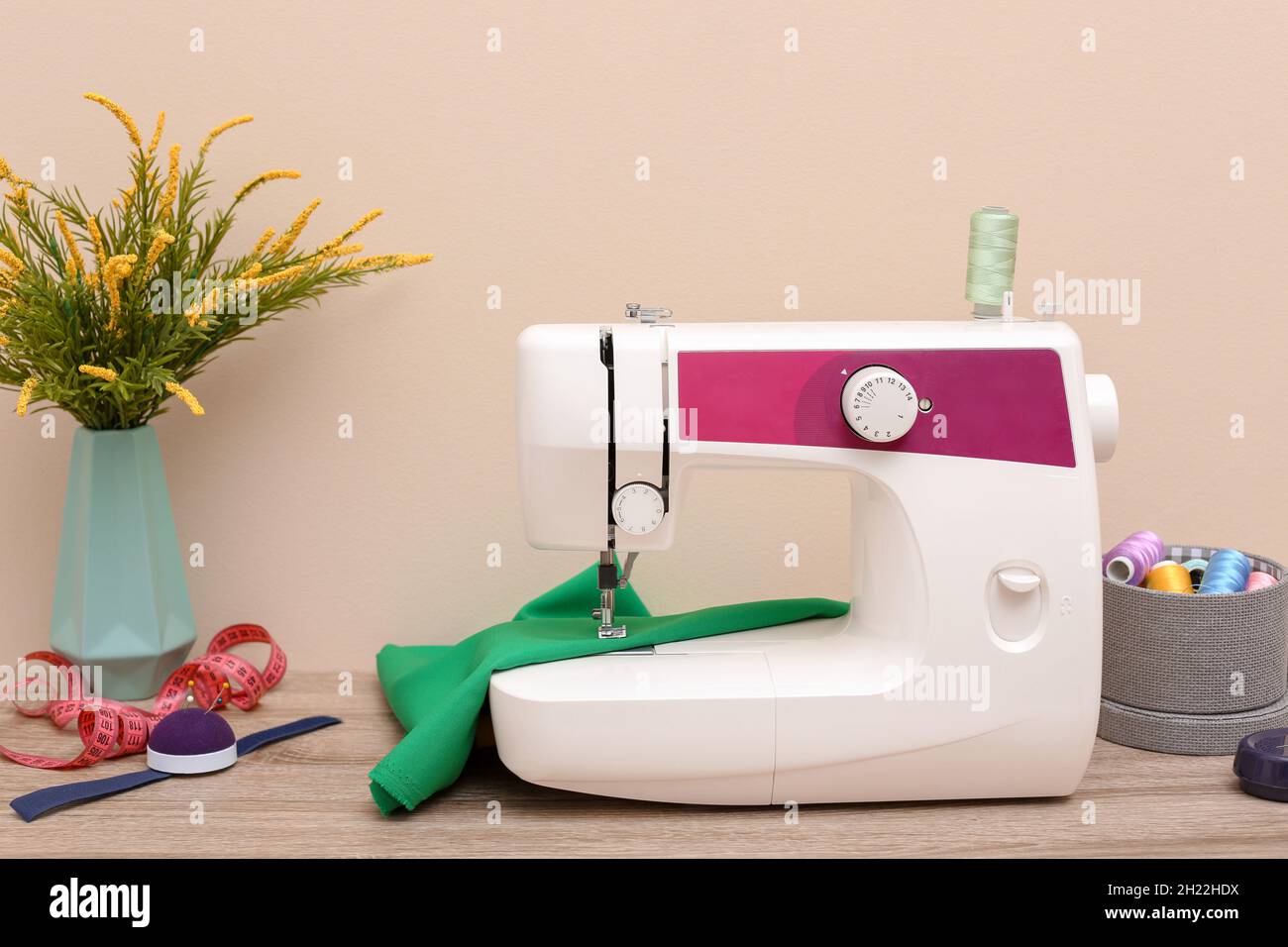 Modern sewing machine on table against light background Stock Photo - Alamy