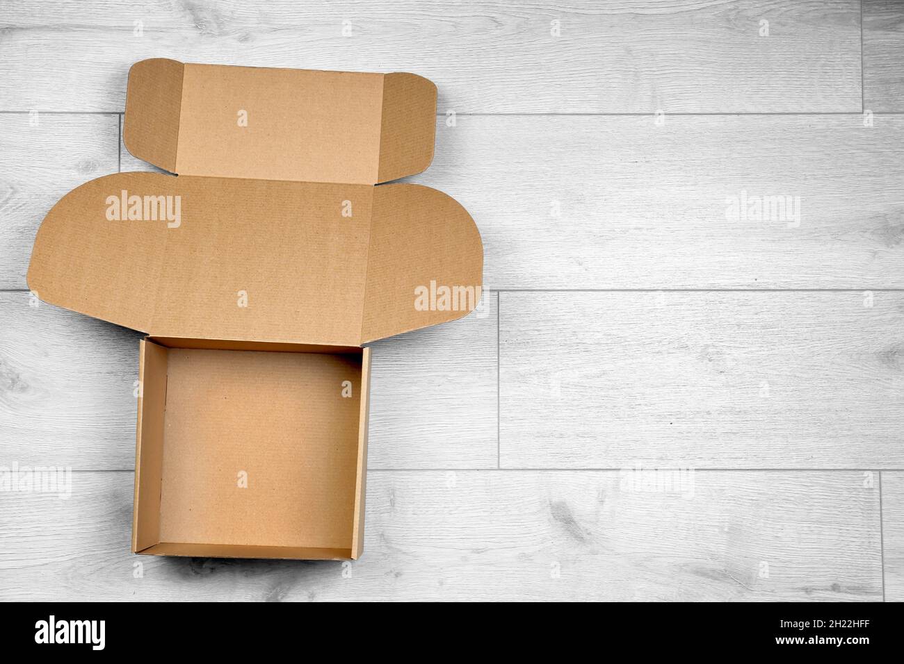 Open empty cardboard box on wooden floor Stock Photo - Alamy