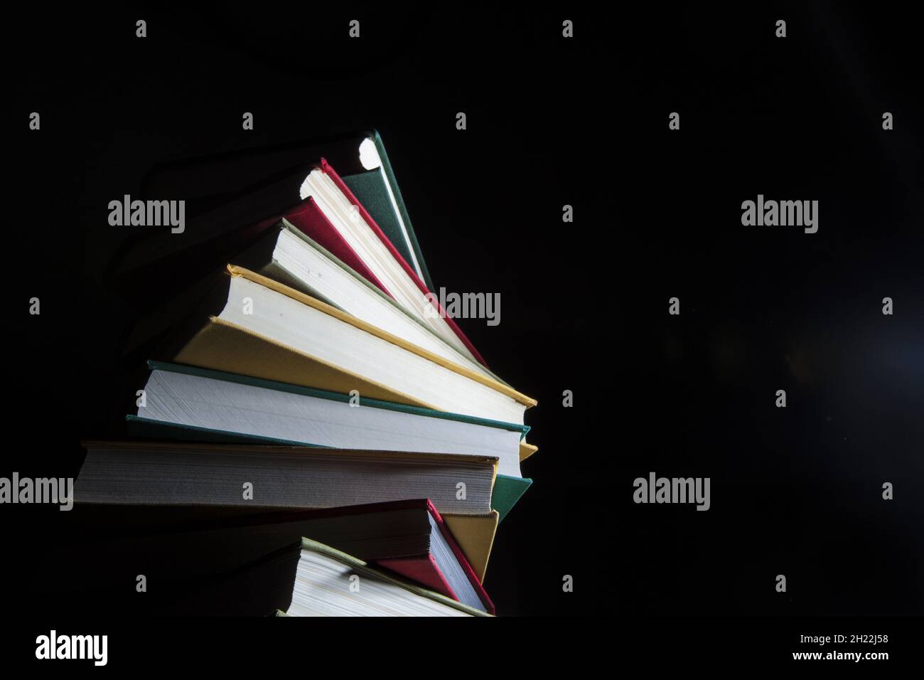 Closeup shot of piled books isolated on a dark background Stock Photo ...