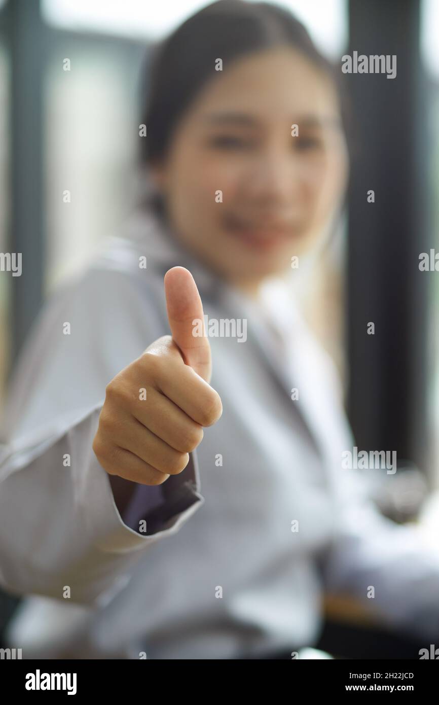 Happy and confident businesswoman gesturing thumbs up sign in office ...