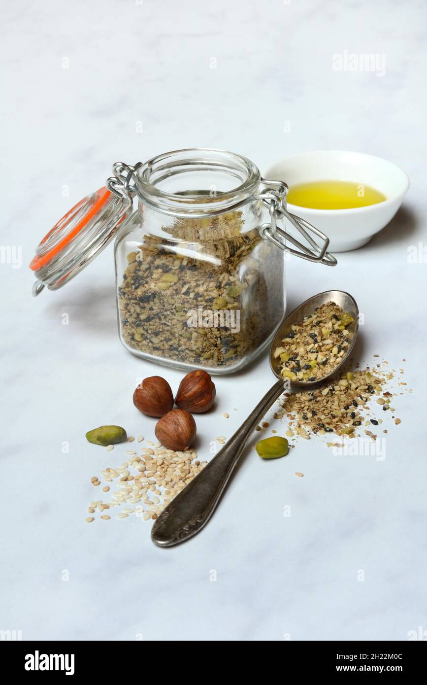 Dukkah, Arabic spice mix in glass container and spoon, nuts and small ...