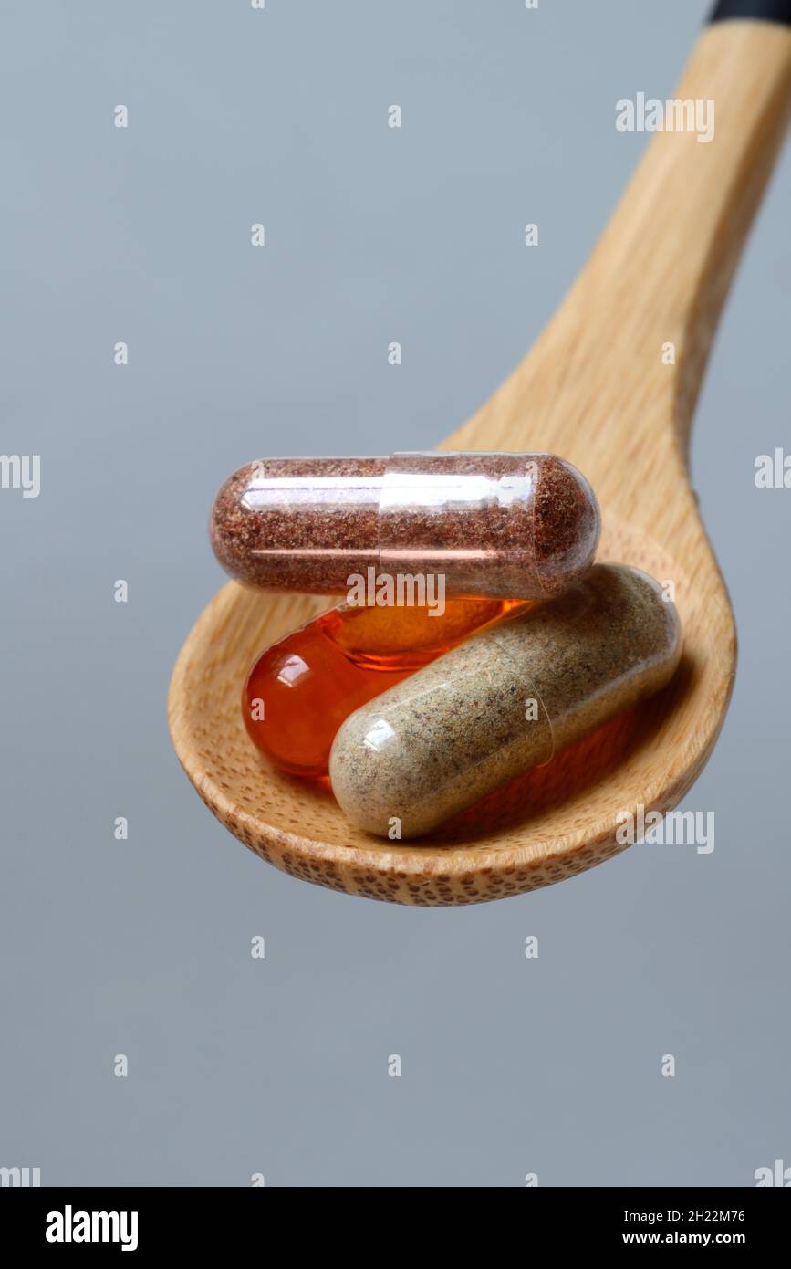 Capsules with food supplement and omega-3 fatty acid in wooden spoon ...