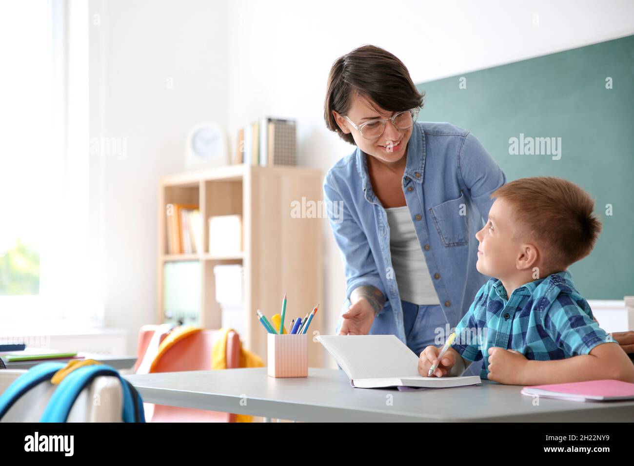 Female teacher helping child with assignment at school Stock Photo - Alamy