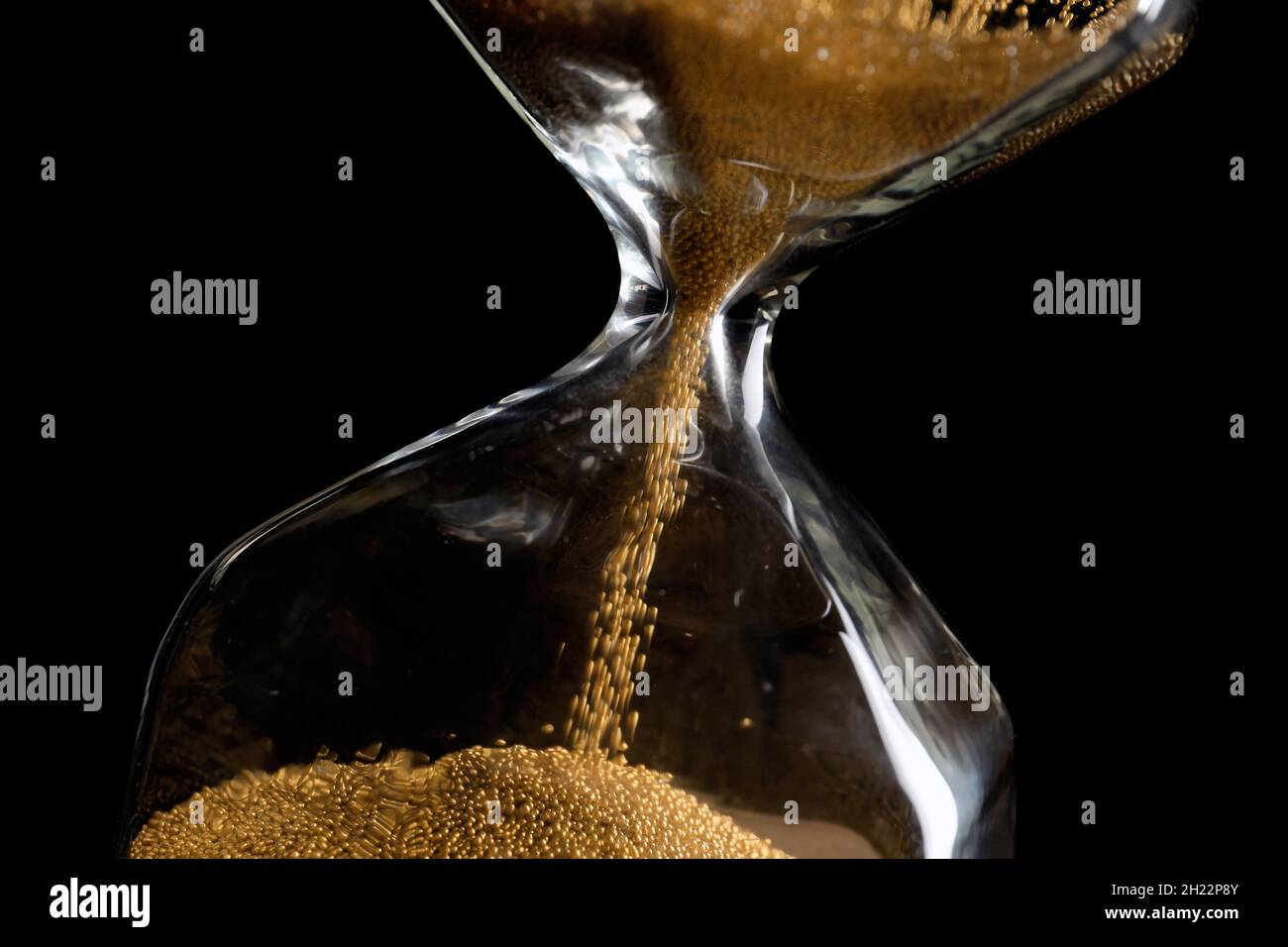 Hourglass with flowing sand on dark background, closeup. Time ...