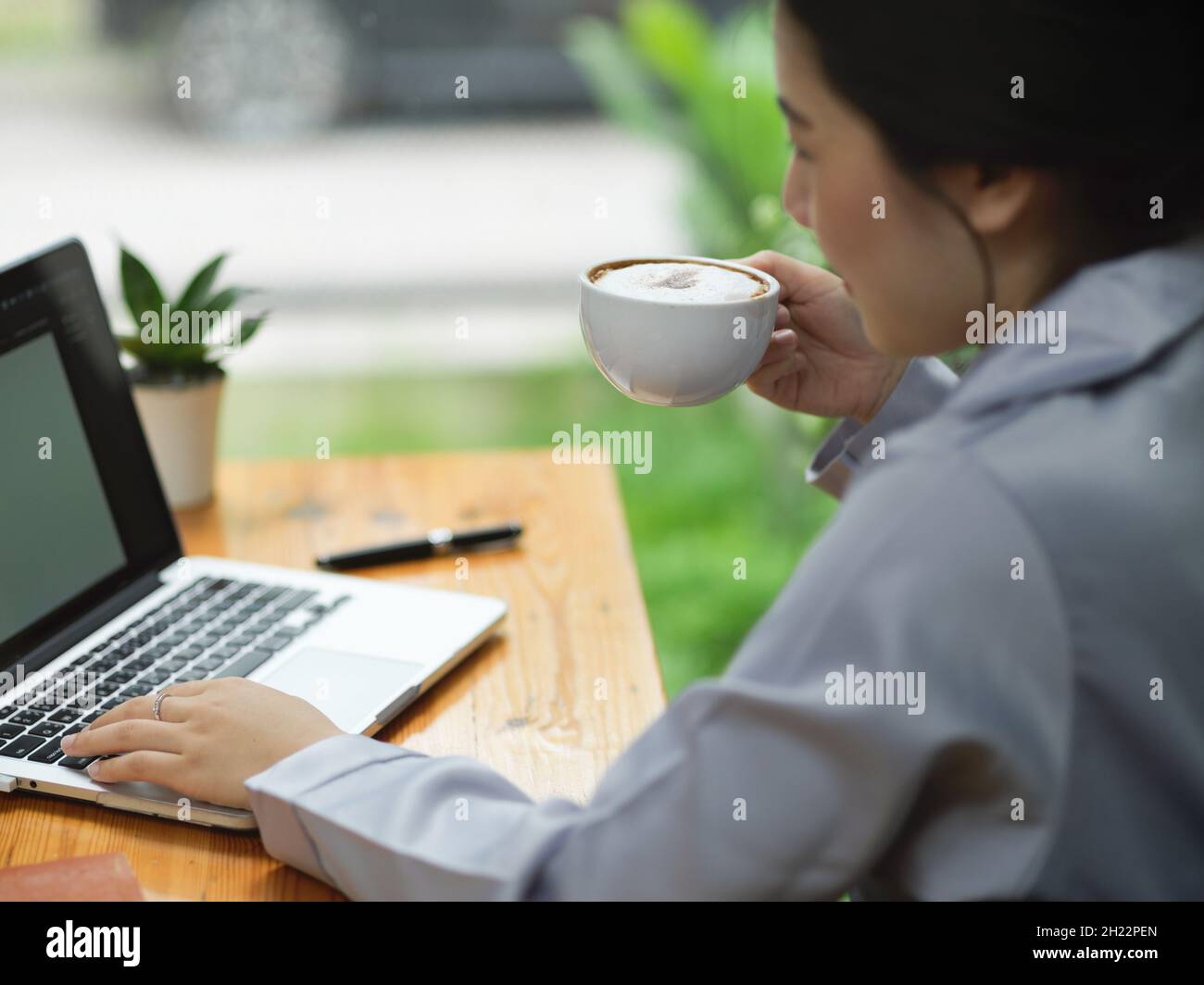 Young businesswoman drinking and sipping coffee while working on her ...