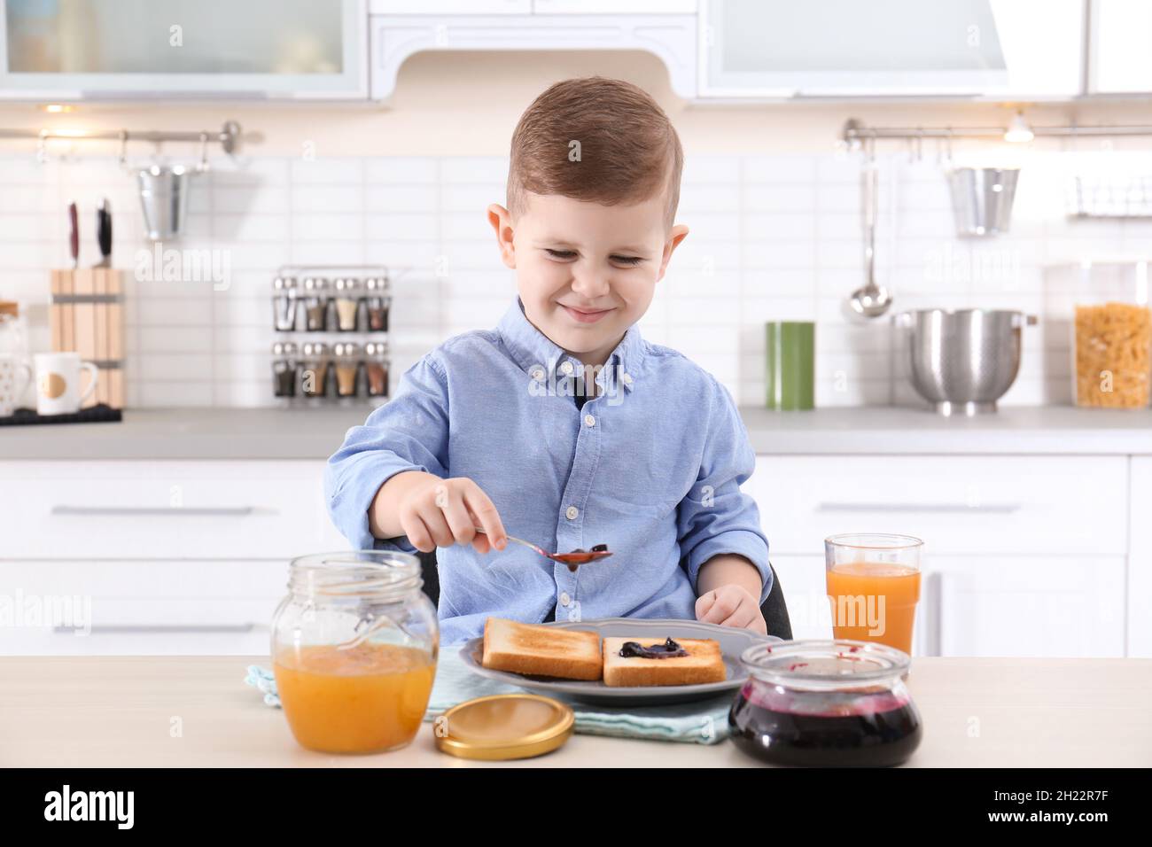 Cute little boy spreading sweet jam onto toast at table Stock Photo - Alamy