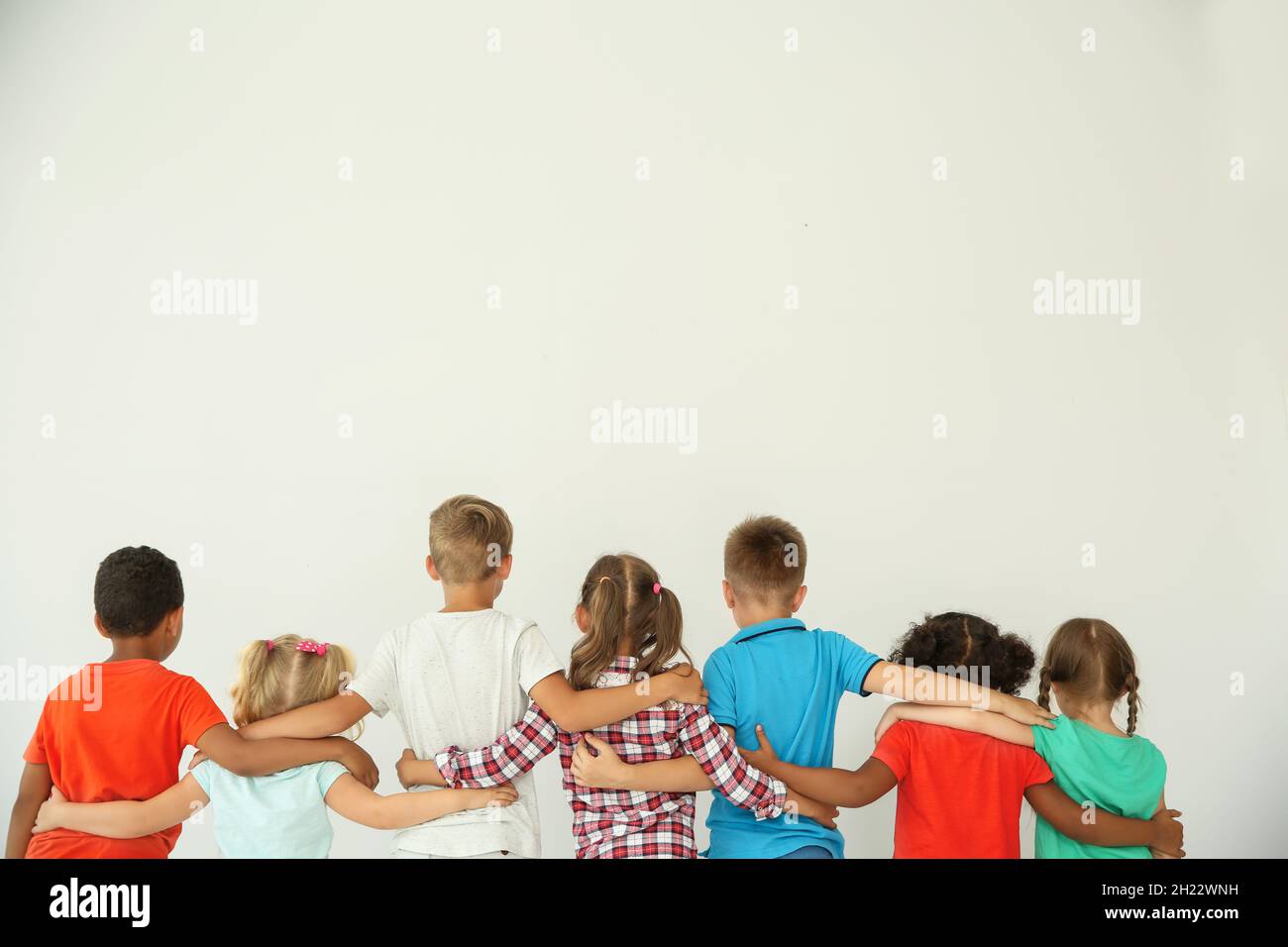 Little children hugging each other with hands on light background ...