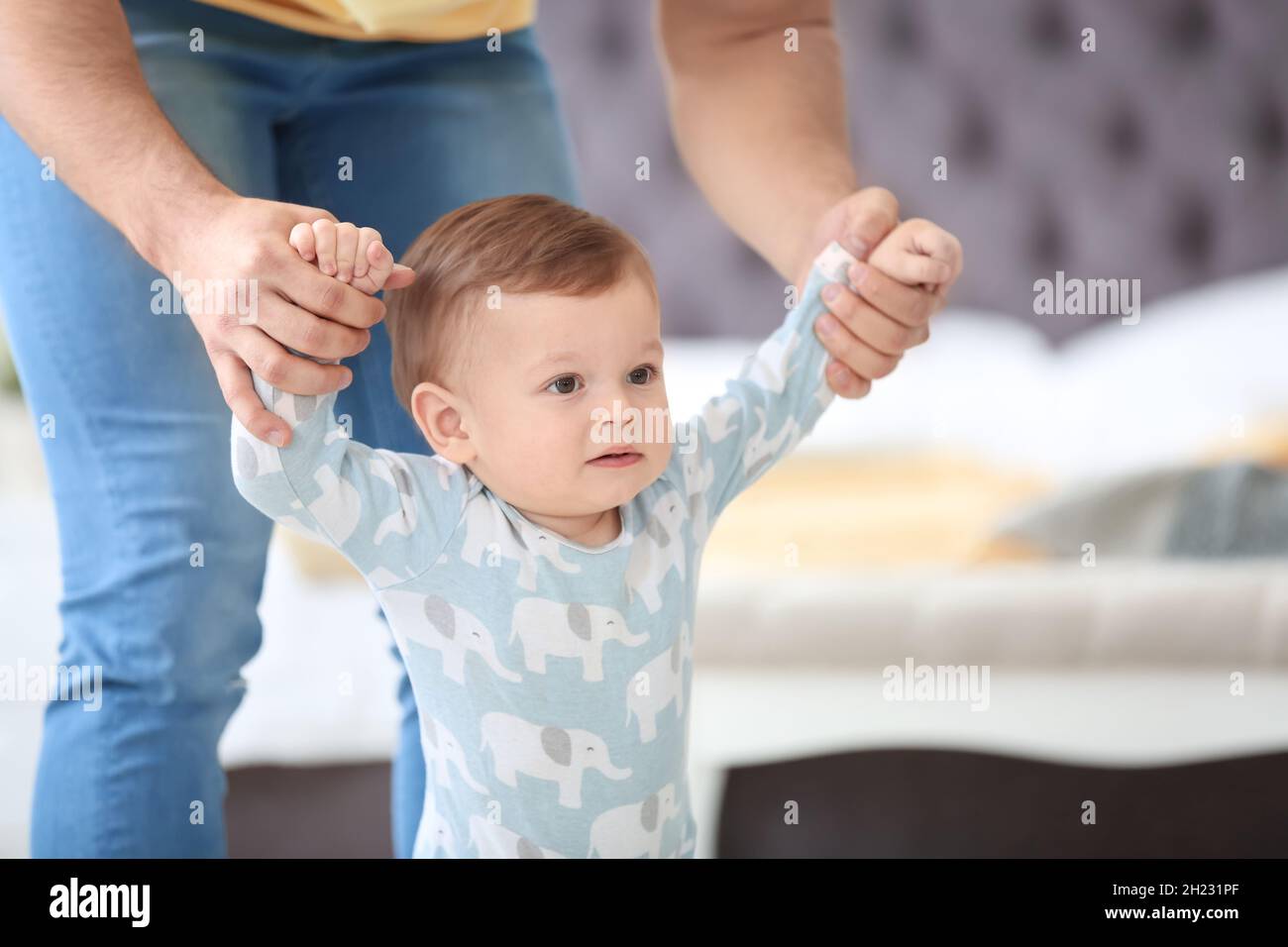 Baby taking first steps with father's help at home Stock Photo - Alamy