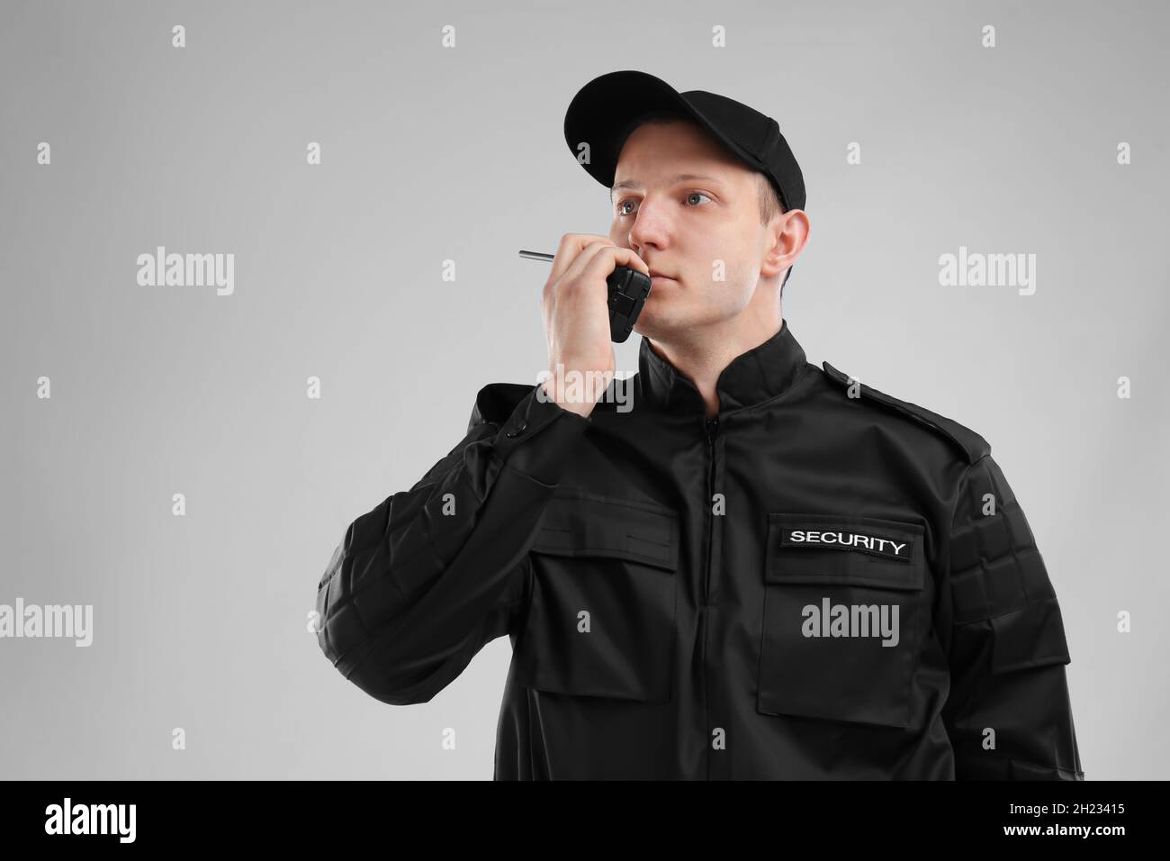 Male security guard using portable radio transmitter on color ...