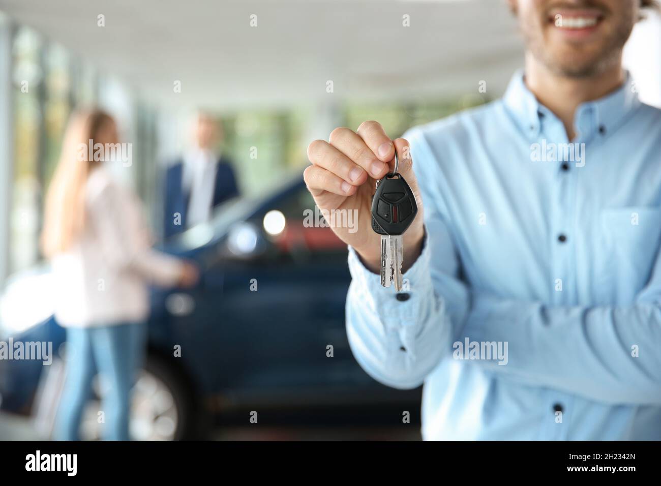 Salesman with car keys in modern auto dealership, closeup Stock Photo ...