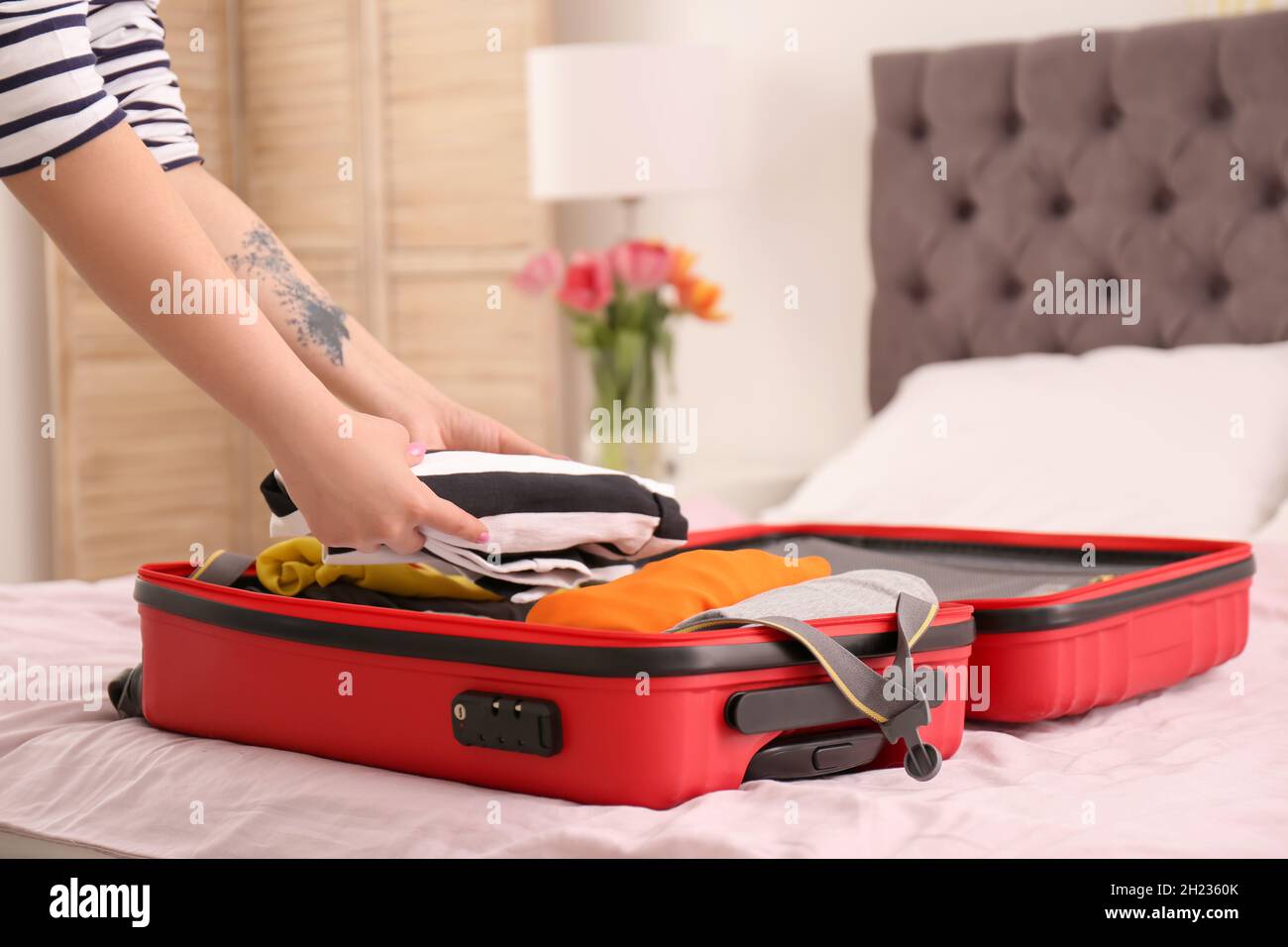 Young woman packing suitcase on bed Stock Photo - Alamy