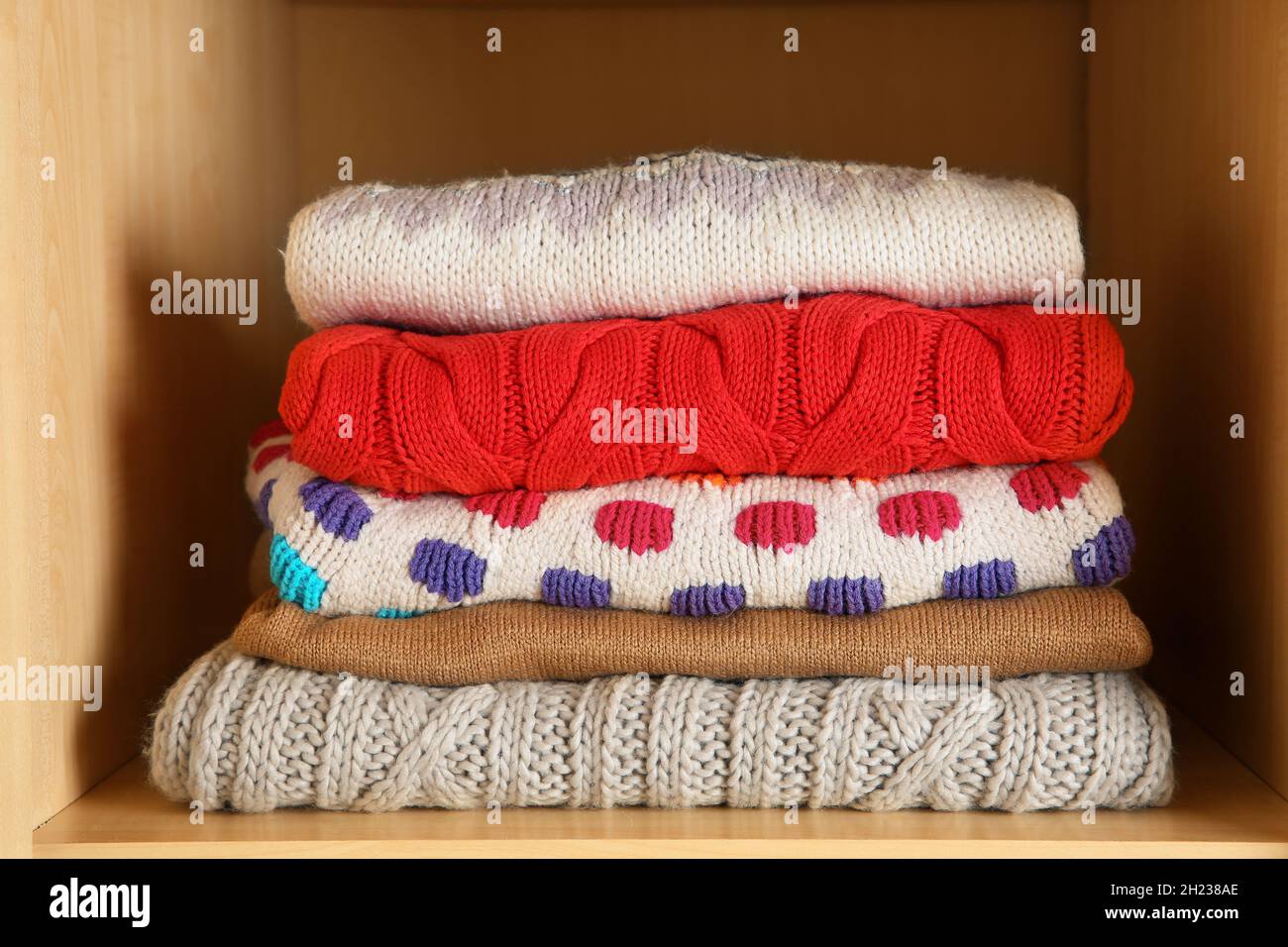 Stack of folded winter clothes on shelf in wardrobe Stock Photo - Alamy