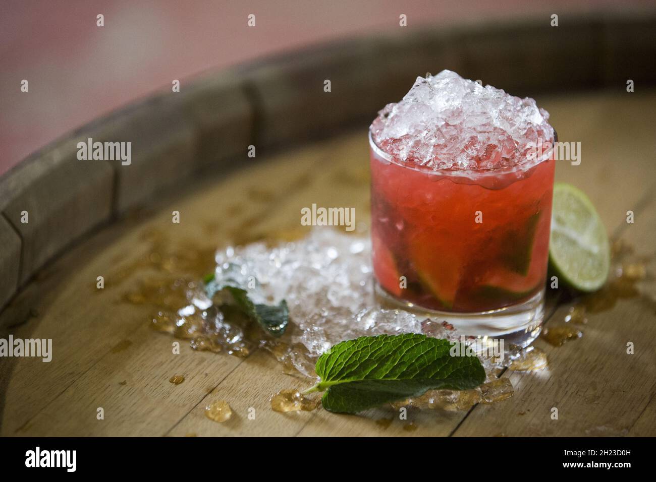 Closeup shot of a glass of red alcohol cocktail on a wooden barrel ...