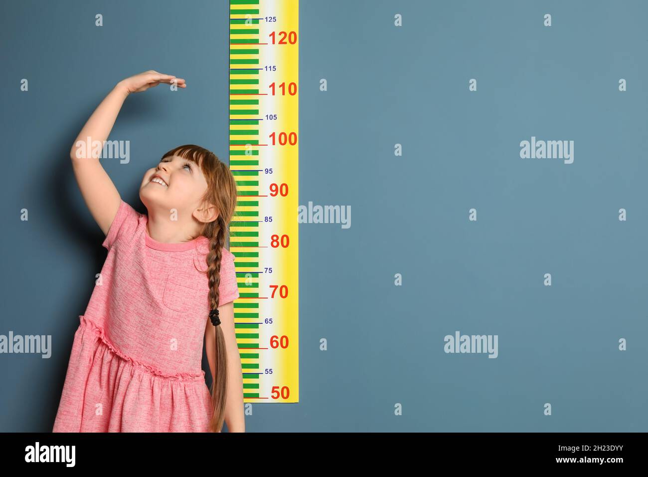 Little girl measuring her height on color background Stock Photo - Alamy