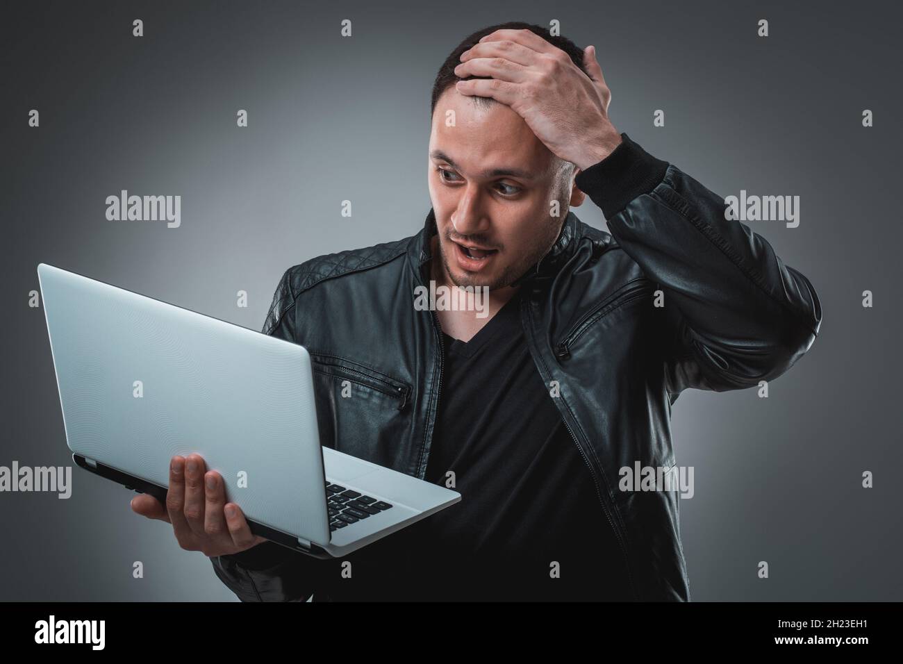 Portrait of young handsome man using laptop, wearing black leather ...